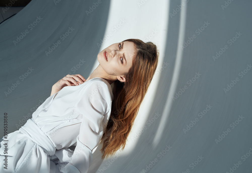 Red-haired Woman in a white dress In a bright room side view and a ...