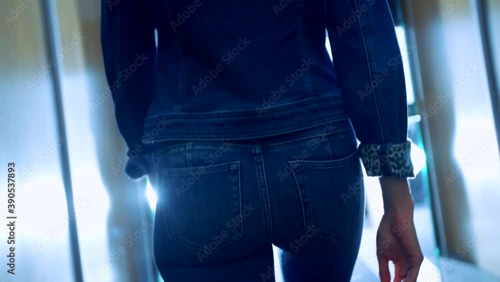 camera shoots female model wearing jeans and denim jacket walking from ...