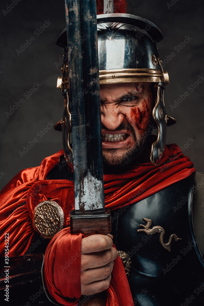 Savage roman barbarian with blood on his face looks at camera holding ...