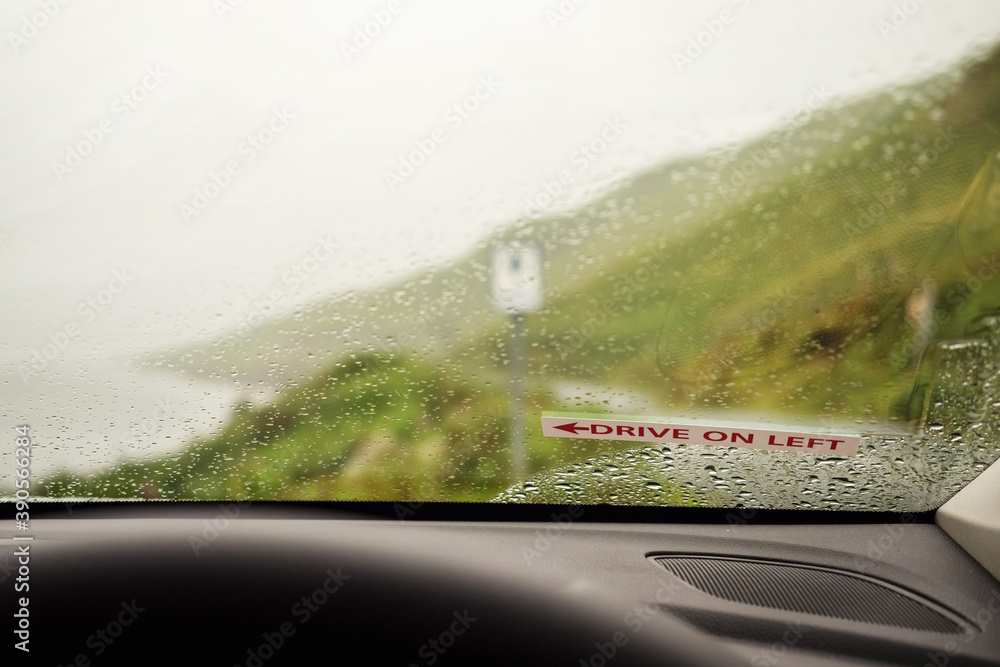Sign DRIVE ON THE LEFT and arrow on a front glass of a car covered with ...