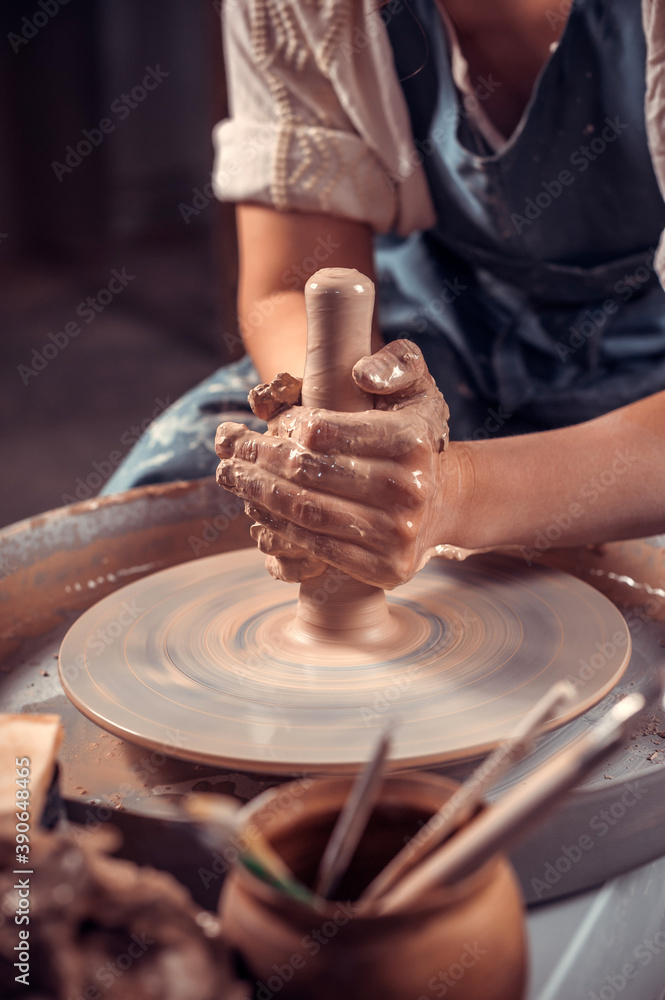Hands of the master potter and vase of clay on the potter's wheel close ...