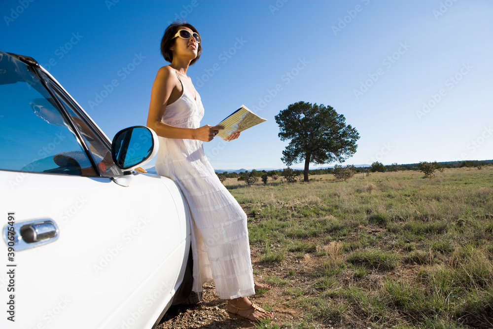 Native American woman by a convertible sports car on desert dirt road ...