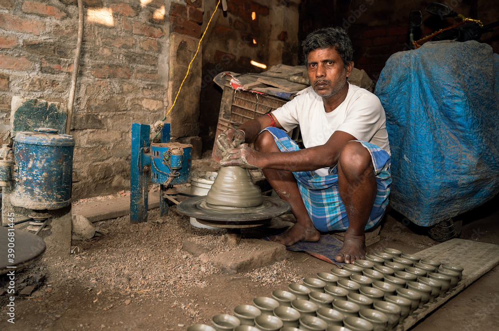 Indian potter making small pot or Diya for Diwali with clay on potters ...