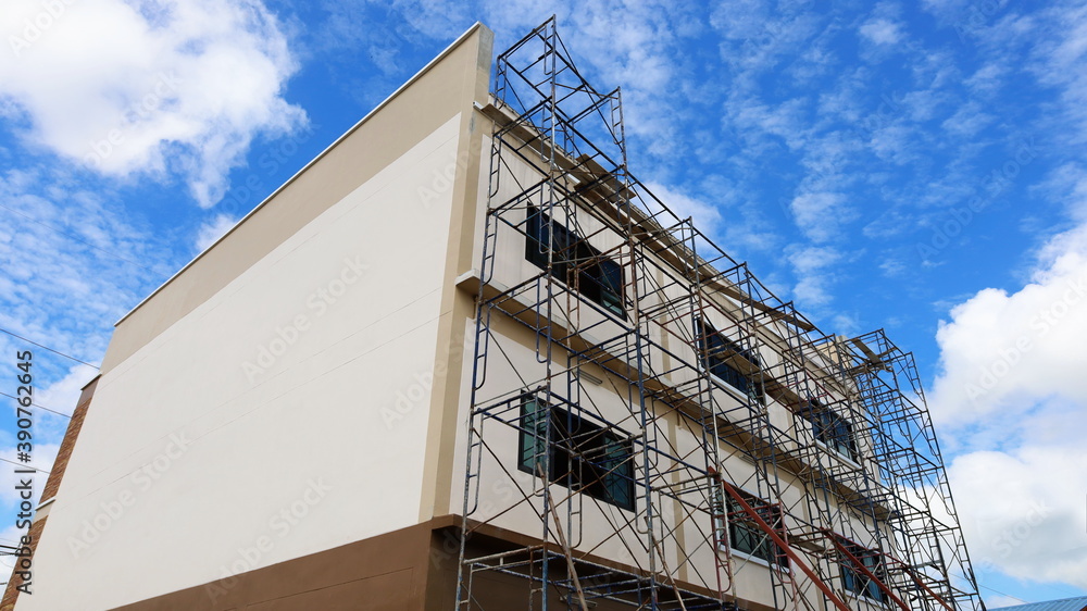 Scaffolding built next to the new building. On a blue sky background ...