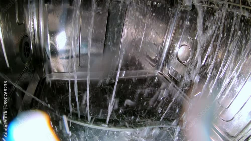 Dishwasher starts to operate and stainless arm rotates shooting water ...