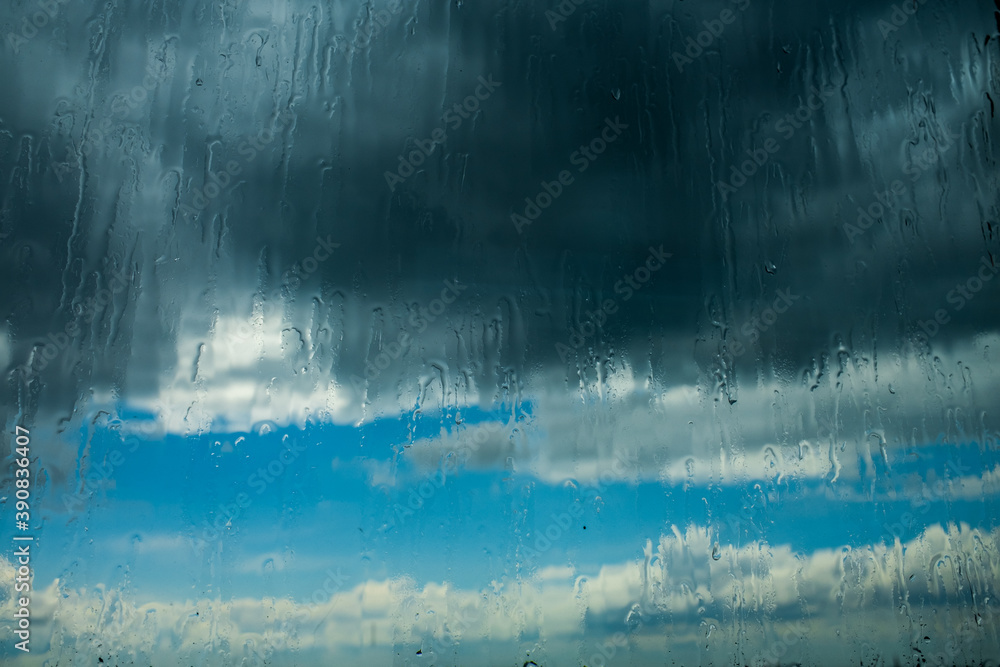 view through a window during rain. rainwater is running over the window ...