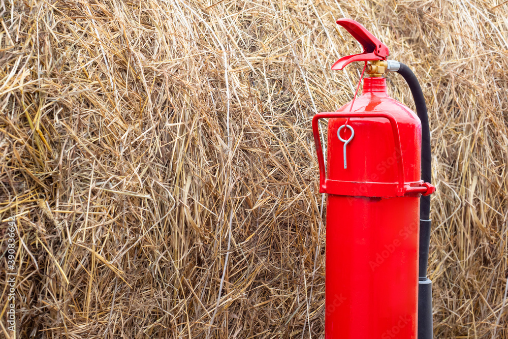 Fire extinguisher next to a haystack. Red fire extinguisher on a dry ...