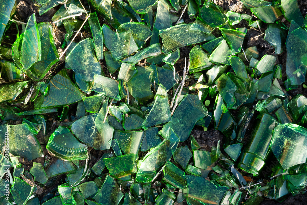Shards of crushed emerald green glass bottles on black lava rock and ...