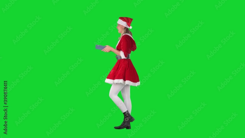 Side view of young happy Santa girl carrying gift behind back giving it ...