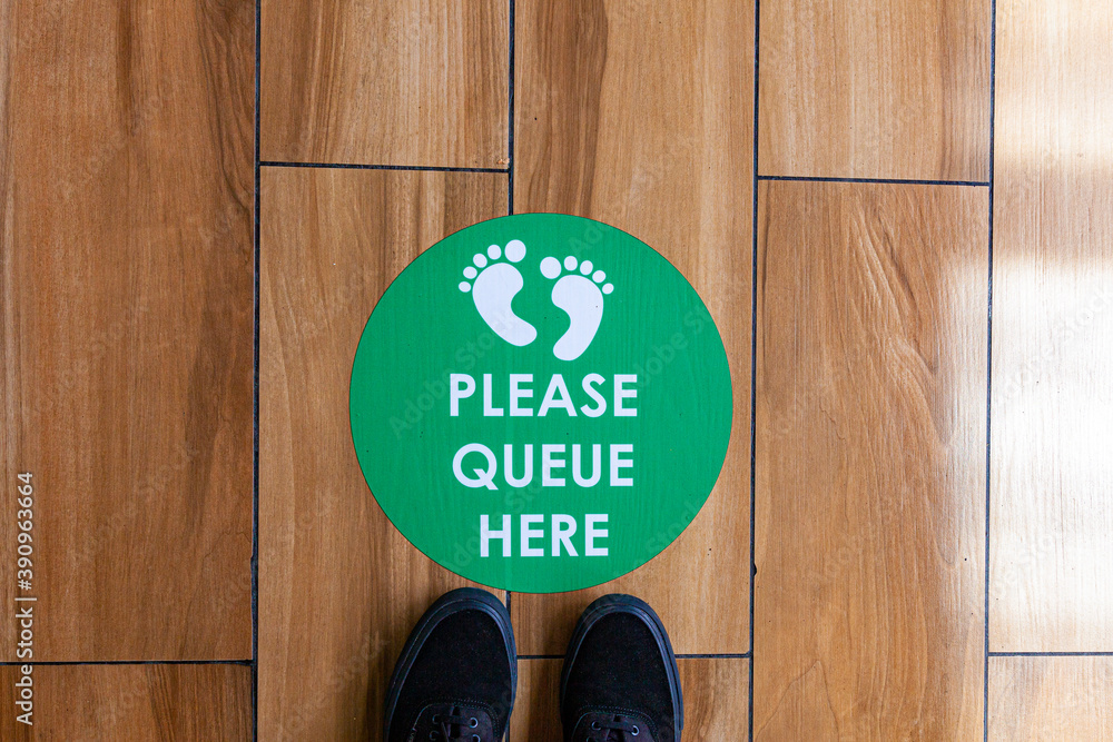 sign on wooden floor with 2 feet in sneakers. please queue here sign ... sign on wooden floor with 2 feet in sneakers. please queue here sign ...