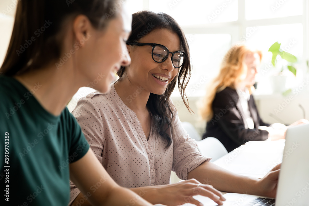 Effective partnership. Smiling multiethnic female colleagues using ...