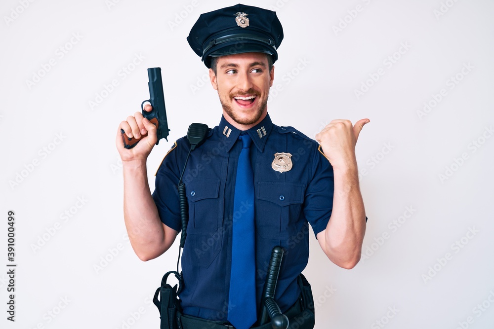 Young caucasian man wearing police uniform holding gun pointing thumb ...