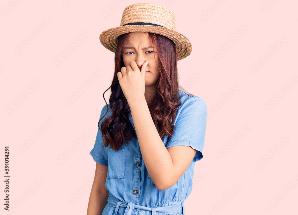 Young beautiful chinese girl wearing summer hat smelling something ...