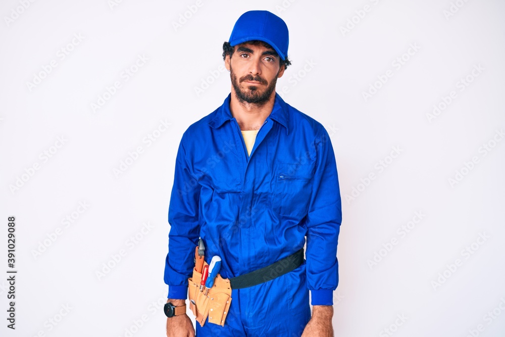 Handsome young man with curly hair and bear weaing handyman uniform ...