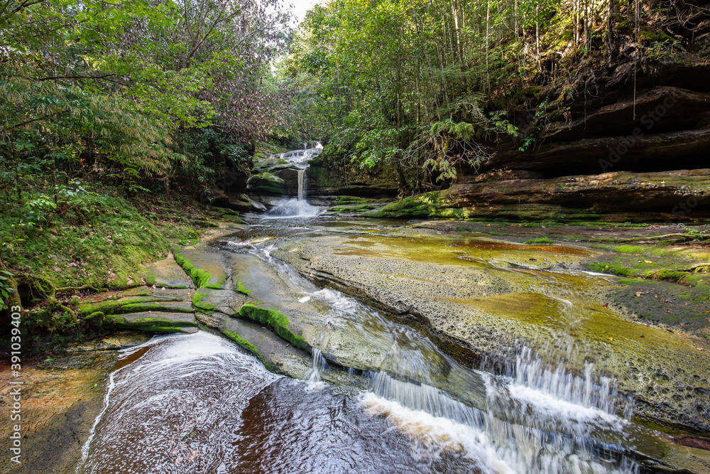 Waterfalls cascading down rocks into the Amazon river surrounded by ...