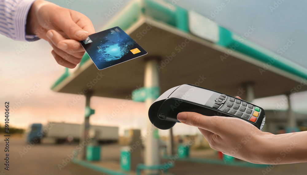 Woman paying for fuel using credit card via payment terminal at gas ...