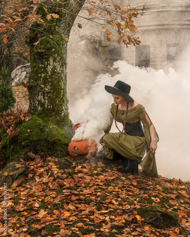 woman witch in green dress with corset and a hat near a medieval castle ...