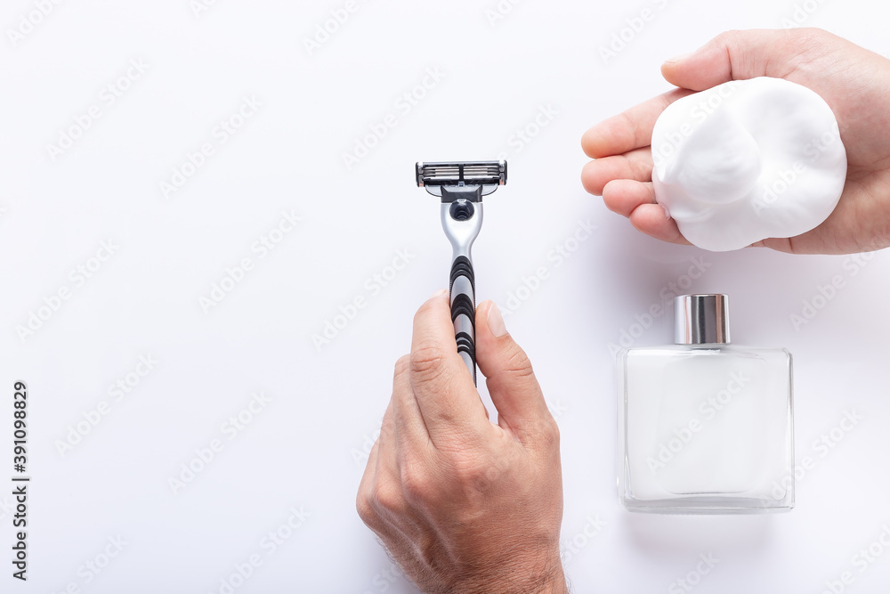 Hands holding razor blade and shaving foam, with after shave isolated ...