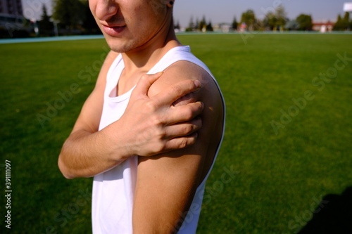 sportsman with shoulder dislocation in turf/sports field, holding his ...