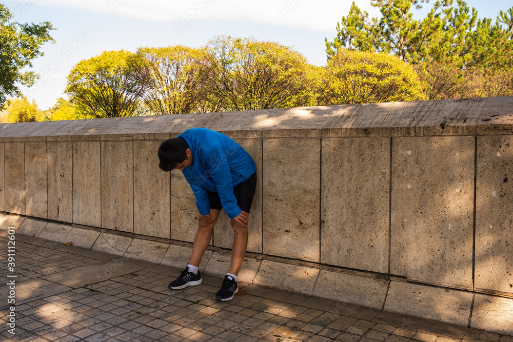 the tired man is resting by leaning against the wall while running ...