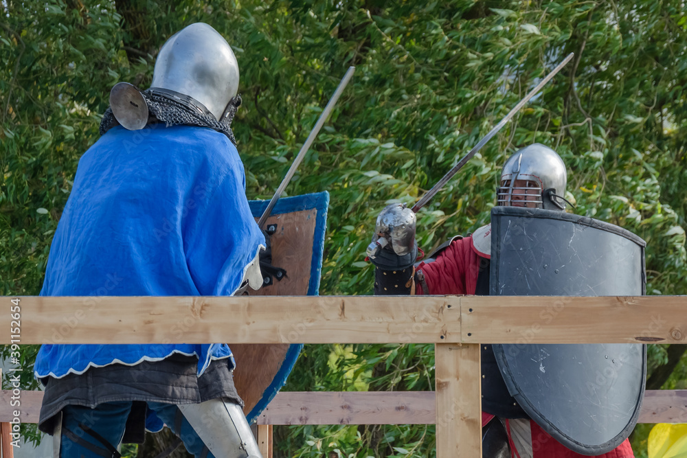 Two foot warriors in heavy medieval armor fight in the arena. Armed ...