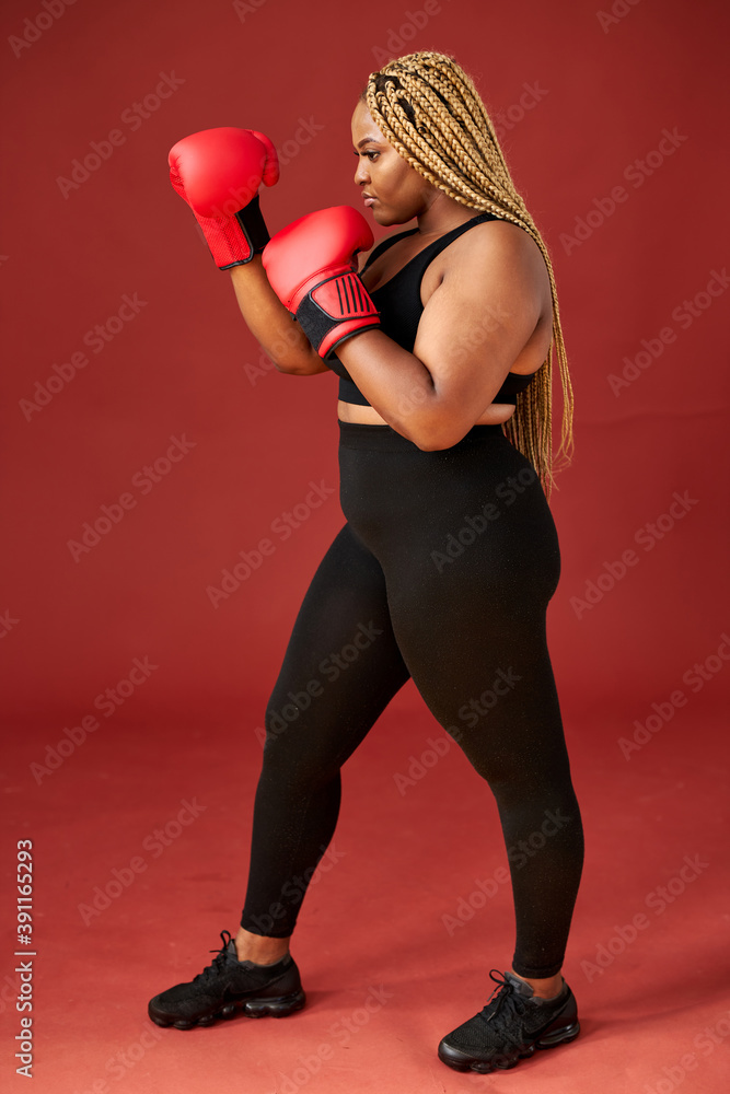 african oversize woman with red boxing mitts isolated on red background ...
