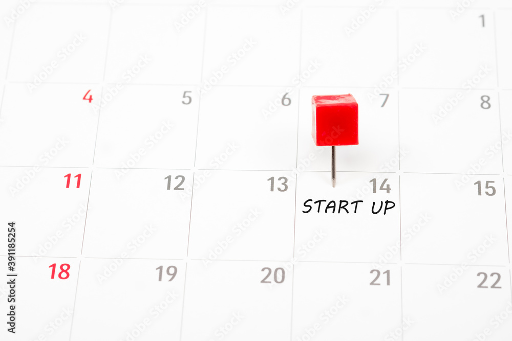 Start up written on a calendar with a red push pin to remind you and ...