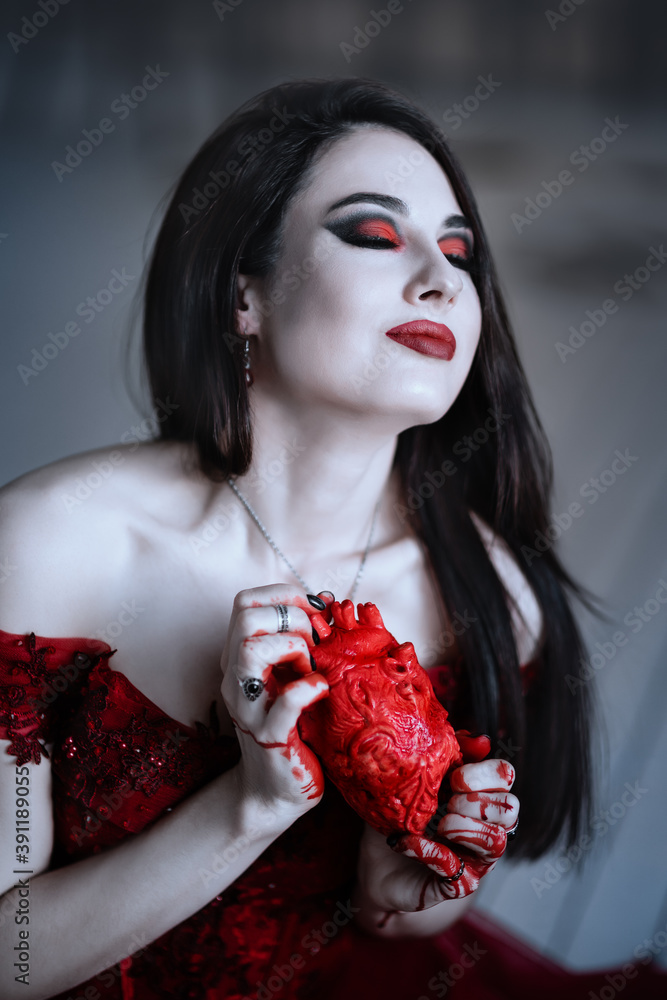 Bloodthirsty female vampire in red dress. Medieval interior Stock Photo ...