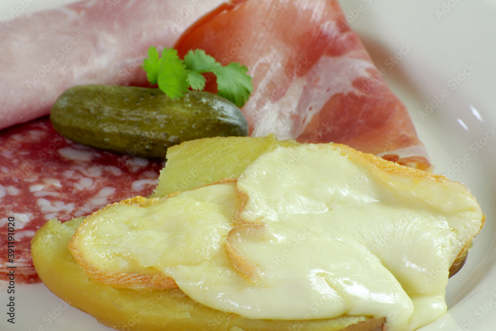 fromage à raclette fondu sur une pomme de terre et charcuterie dans une ...