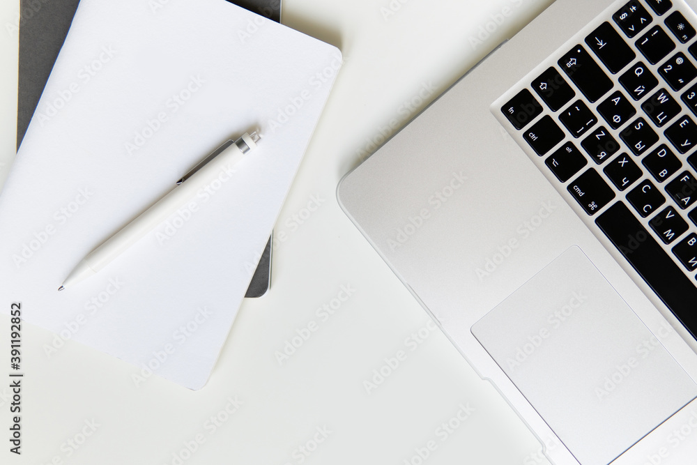 workspace with laptop white and gray notepad and palm leaf and phone ...