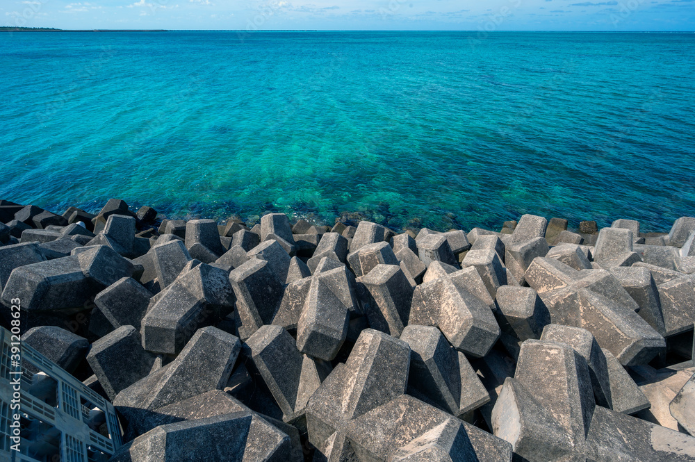 Concrete tetrapod sea defense barrier contrasts with turquoise waters ...