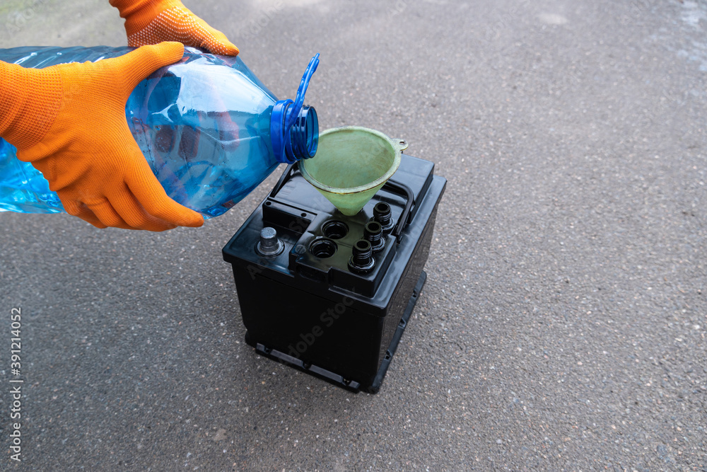 Mechanic adds electrolyte to battery, car battery diagnostics and ...