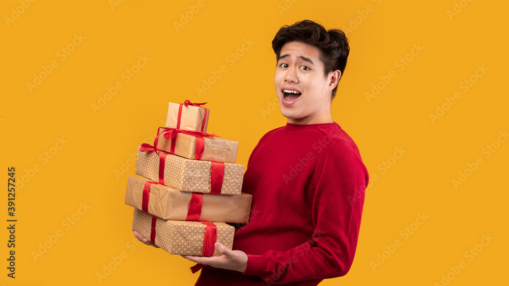 Happy asian man holding stack of present boxes Stock Photo | Adobe Stock