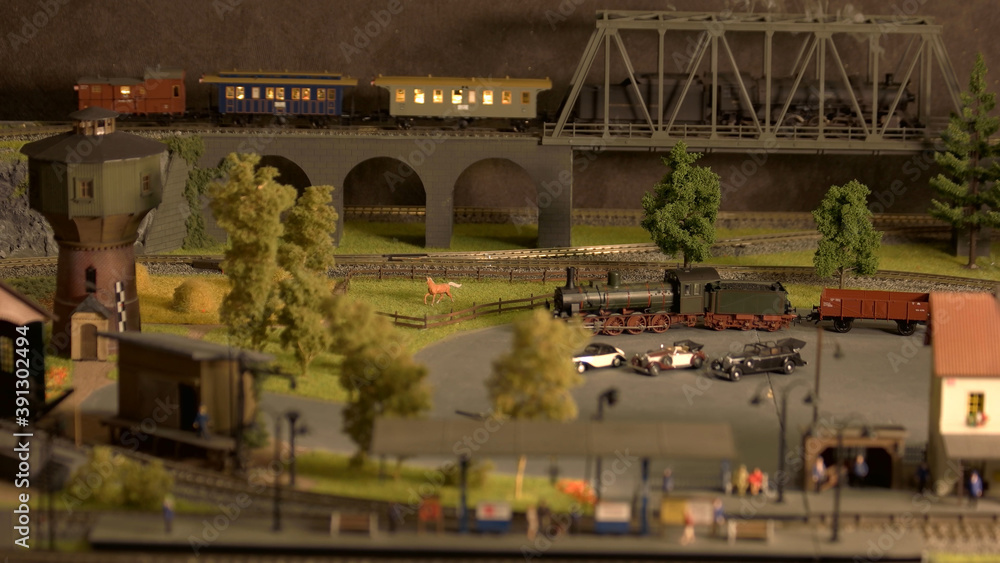 Miniature railway model in retro style. Train with cars, bridge and ...