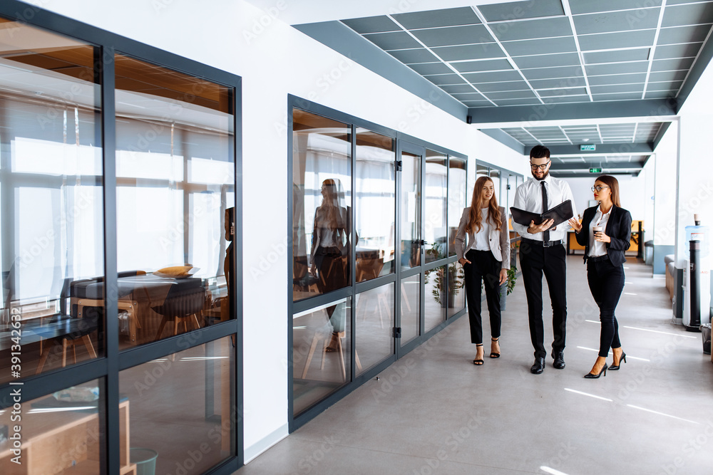 team of businessmen talking and looking at documents while walking ...