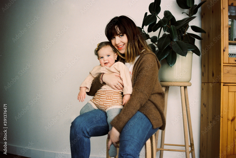 Little one year old girl sitting on mothers lap indoors Stock Photo ...