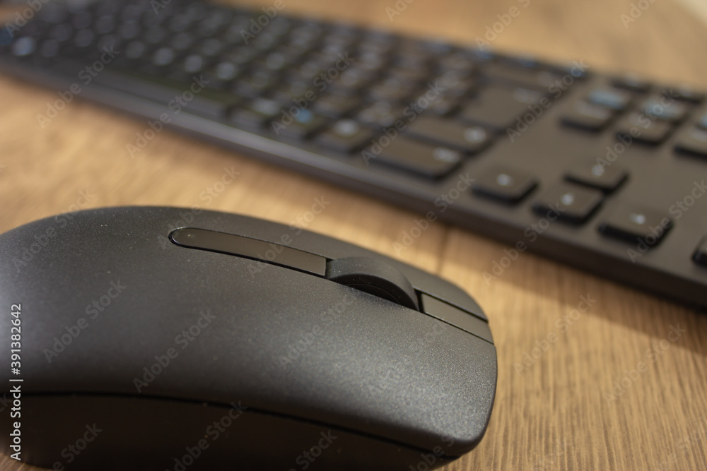 Wireless mouse and keyboard set on top of a wooden office desk, on a ...