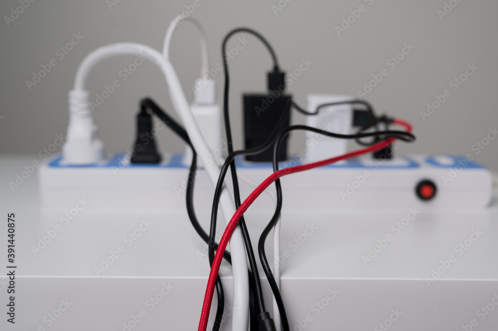 Risk of electric shock Overload. Many electric cable plugged in socket ...