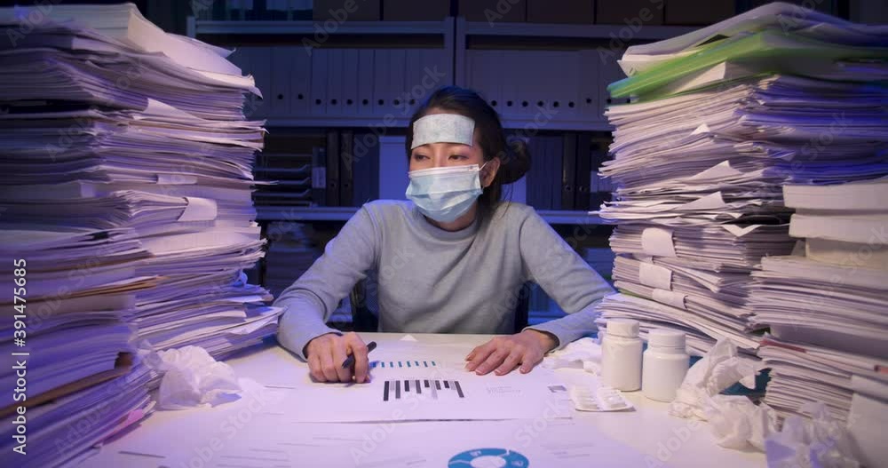 "Sick asian business woman is sitting at desk covered with stack of ...