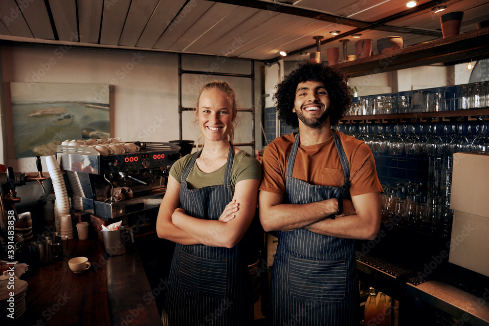 Poster Portrait of young female and male staff wearing apron standing ...