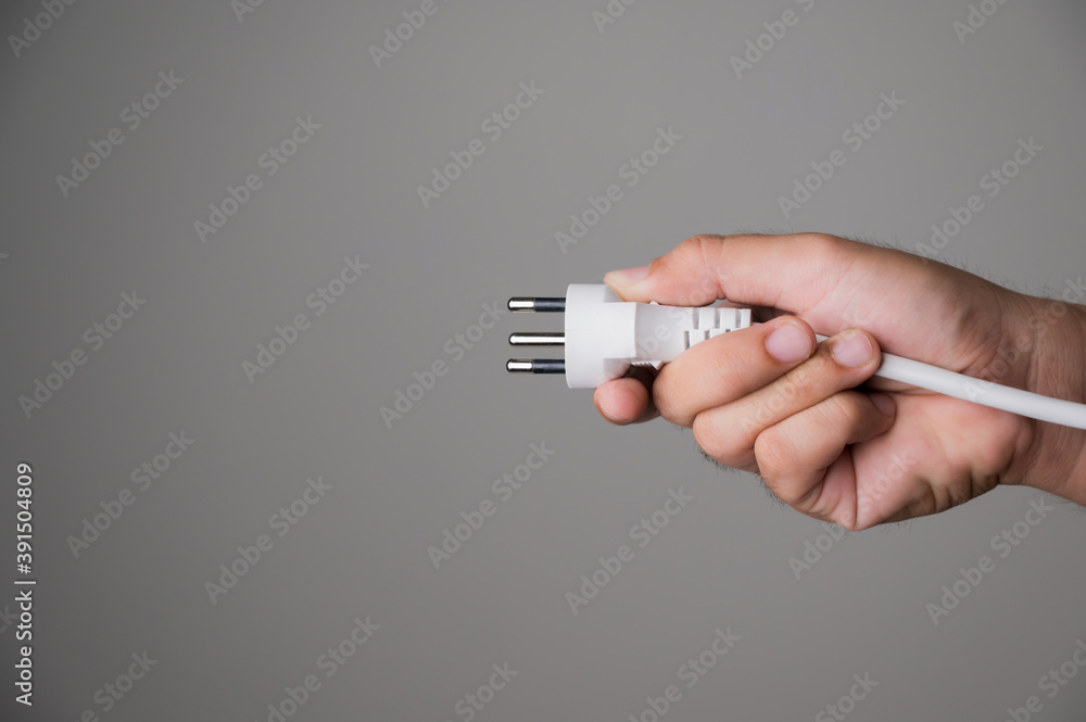 Male hand holding plug cable with copy space. Electrical equipment ...