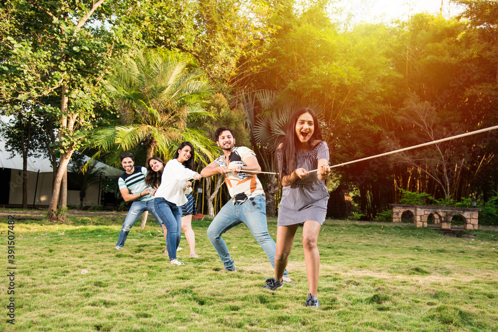 Indian asian young friends playing tug of war or rassi khech outdoors ...