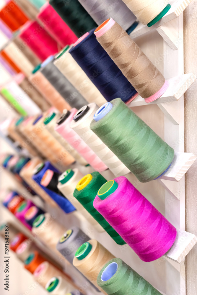 Colorful background of spools, bobbins of threads on wall. Close up ...