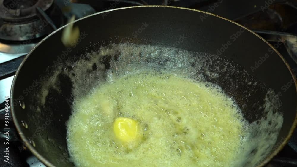 Close-up of piece of butter melting in frying pan. Action. Cooking dish ...