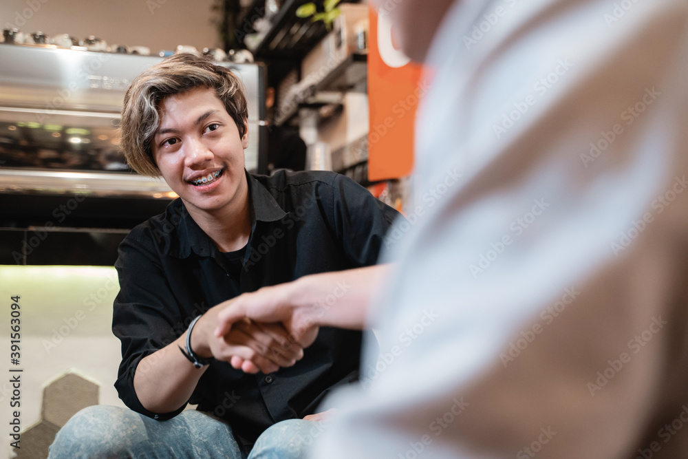 asian young man shake hands with partner when sitting on sofa in coffee ...