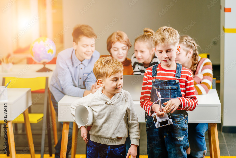 Two different age pupil boys with with projective poster and wind ...