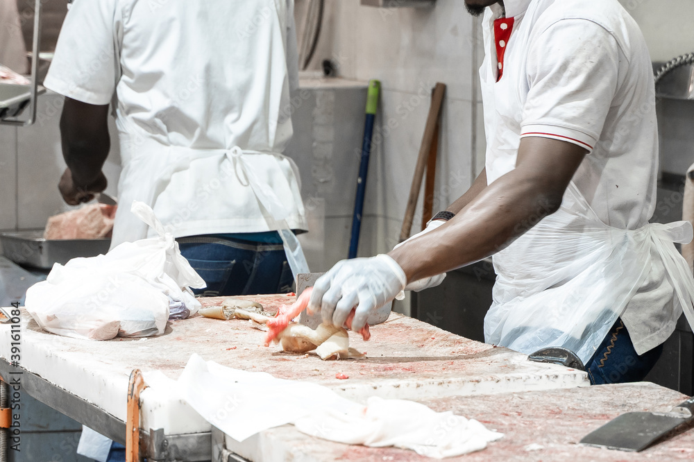 African american butcher cutting meat at counter in butchery. A man ...
