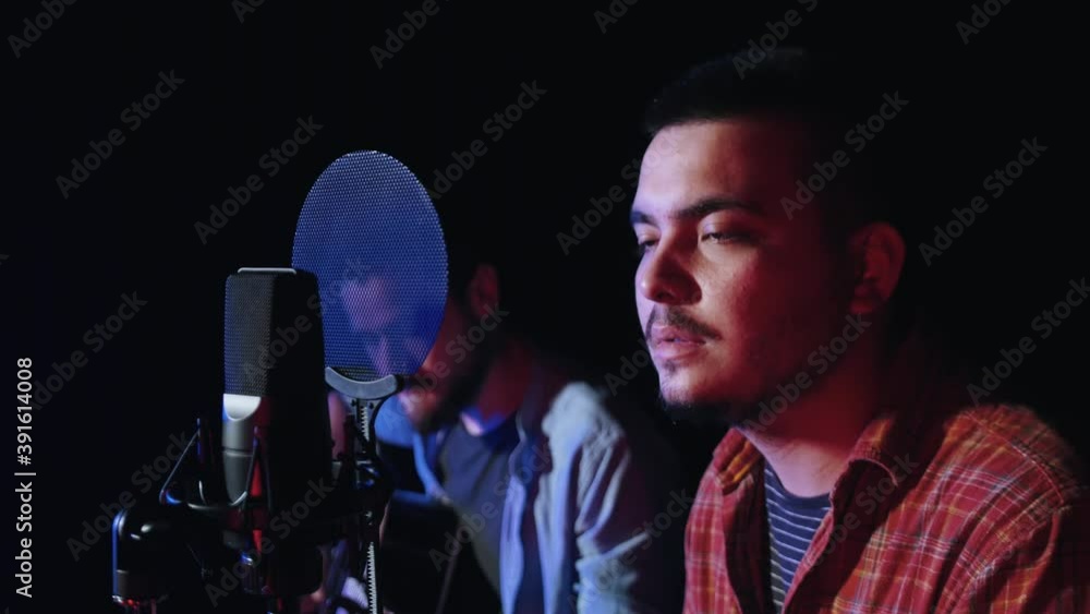 Two men recording a song in the studio - playing guitar and singing in ...