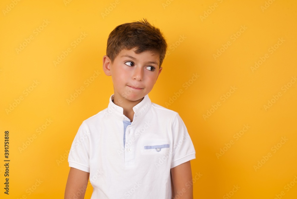 Amazed puzzled Cute Caucasian little boy standing against yellow ...