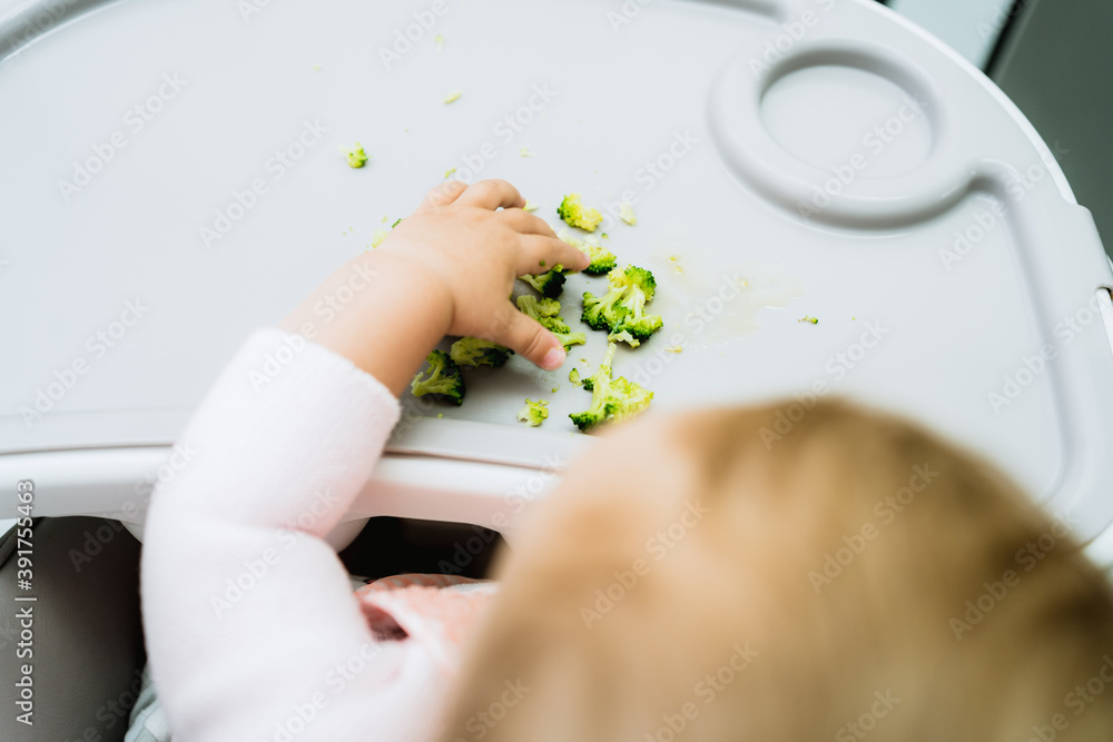 baby eating broccoli with hands in early stages of baby-led weaning ...